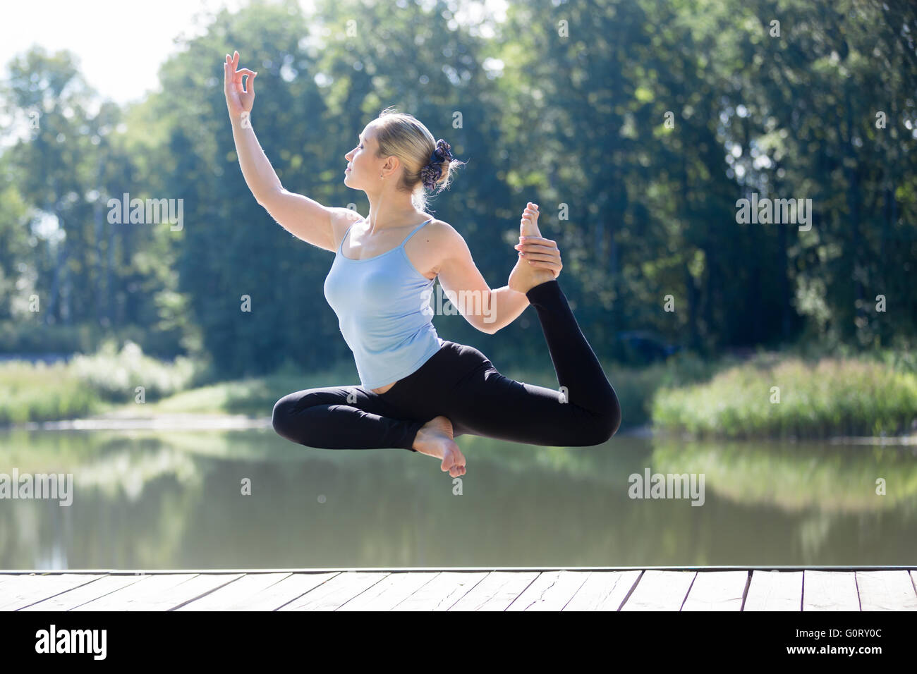 Serene young sporty beautiful woman floating in midair during yoga ...