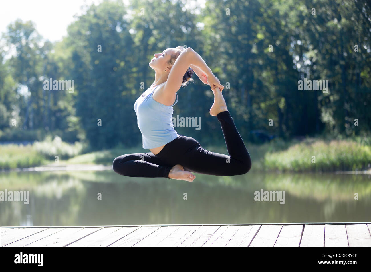 Serene young sporty beautiful woman floating in midair during yoga ...