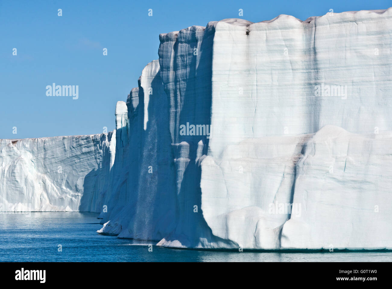 A waterfall coming over the ice cliffs on the edge of the ice cap at ...