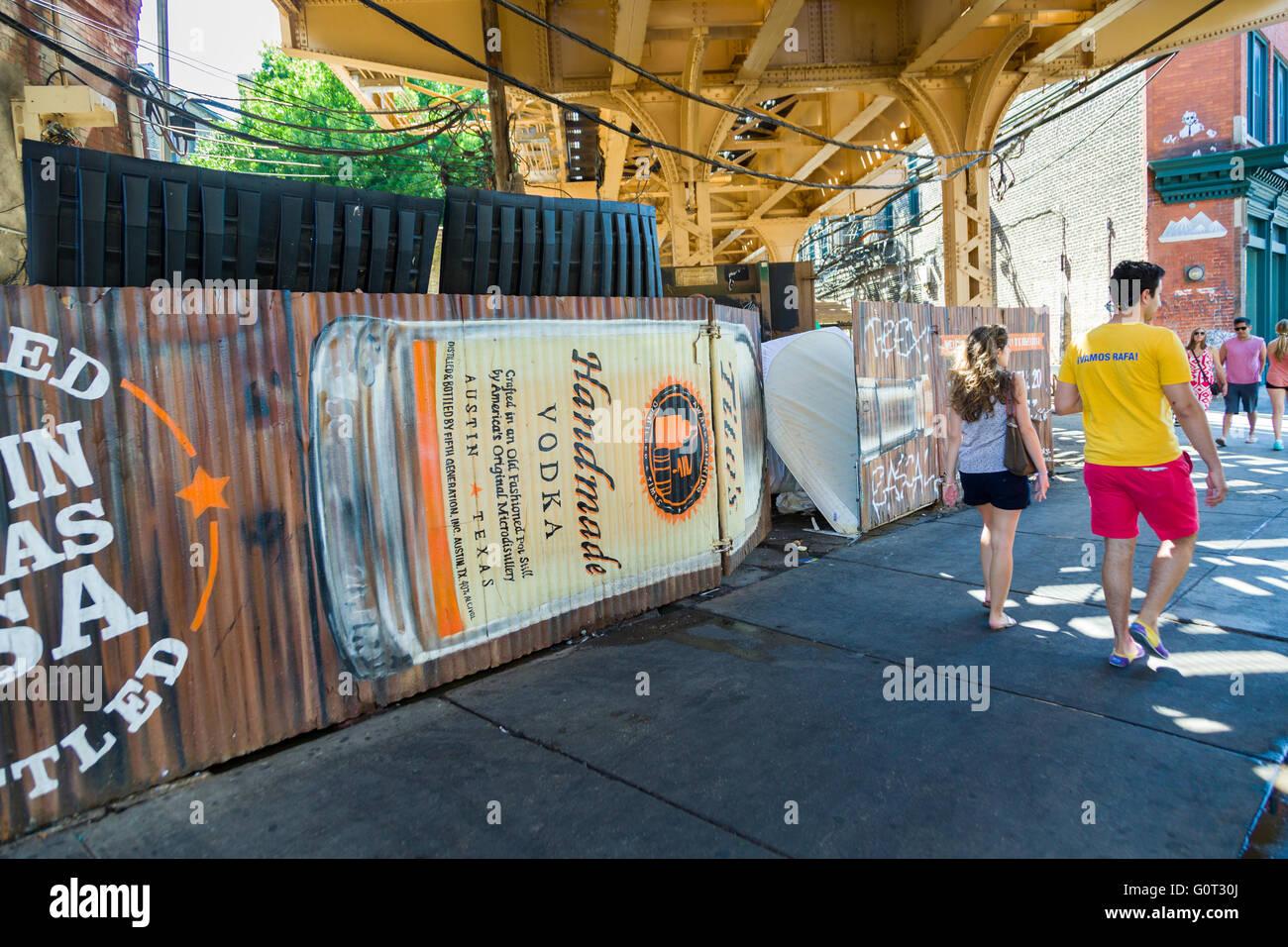 Pedestrians walk past an advertising mural painted alongside a building ...