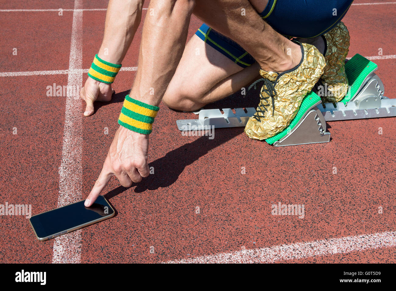 Athlete crouching at the starting line of a running track wearing ...