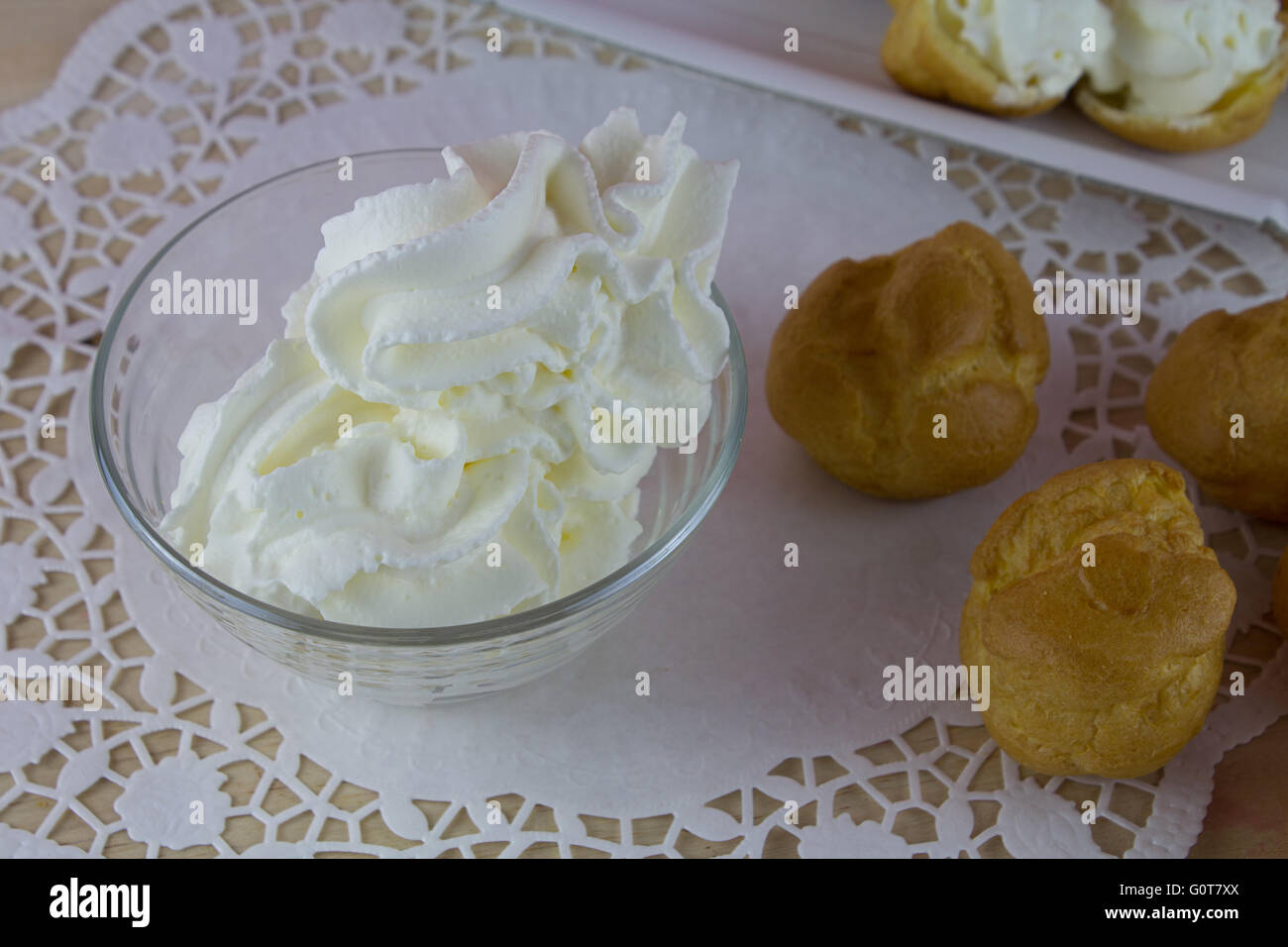 Empty Italian bigne next to fresh cream to fill in, on wooden table ...