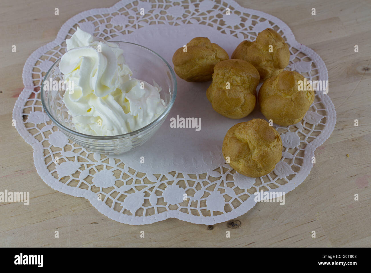 Empty Italian bigne next to fresh cream to fill in, on wooden table ...