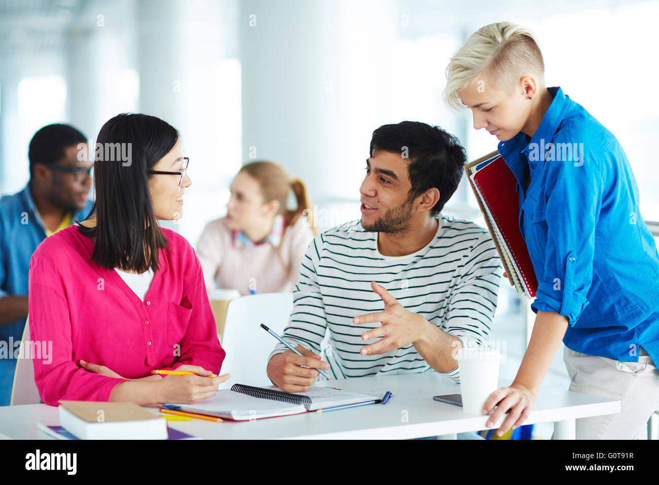 Group of students discussing notes during break Stock Photo - Alamy