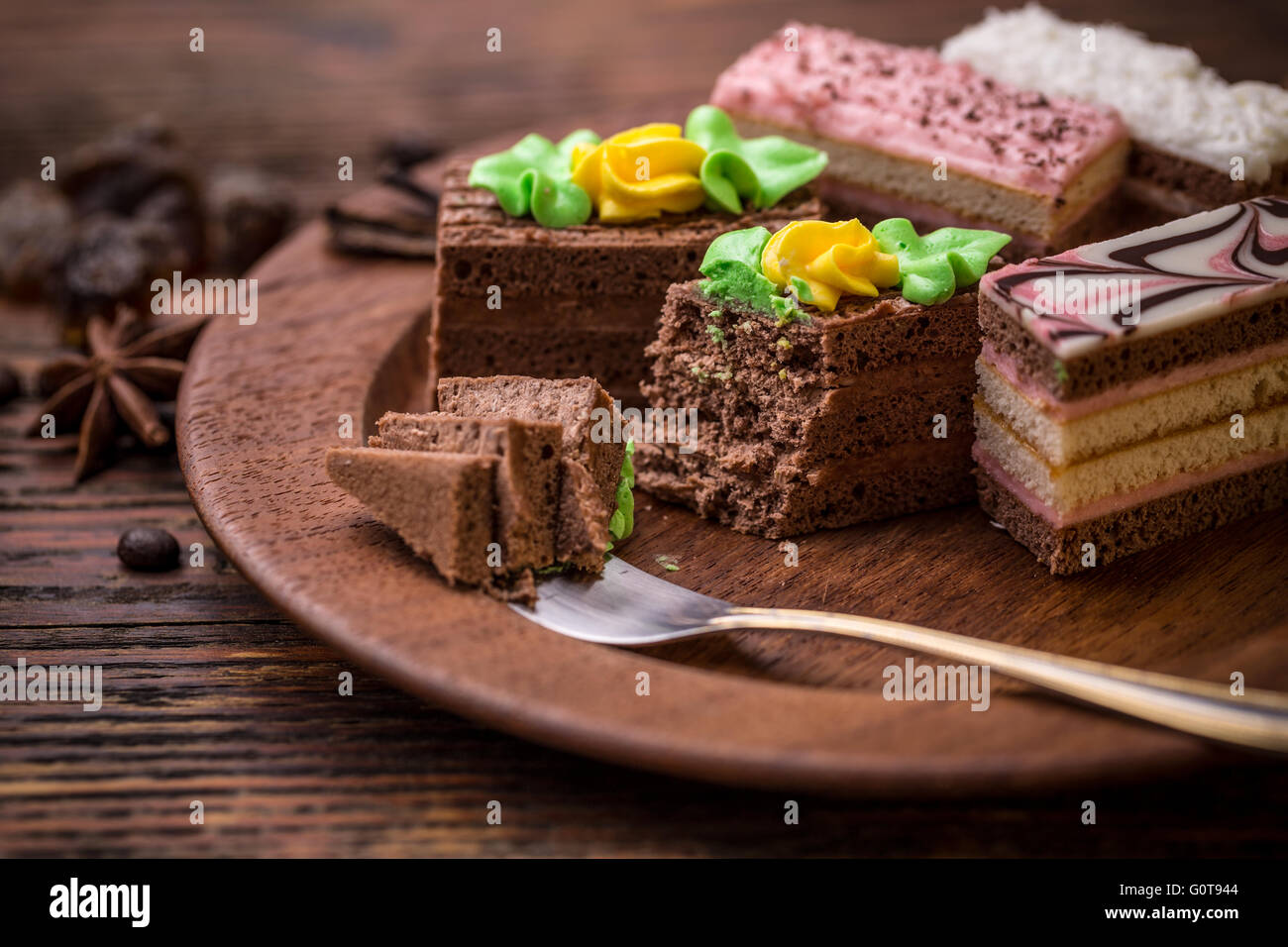 Delicious mini cakes served on wooden plate Stock Photo - Alamy