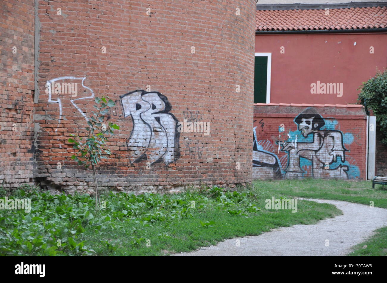 graffiti on brick building facade, image of man on wall, path, Venice ...