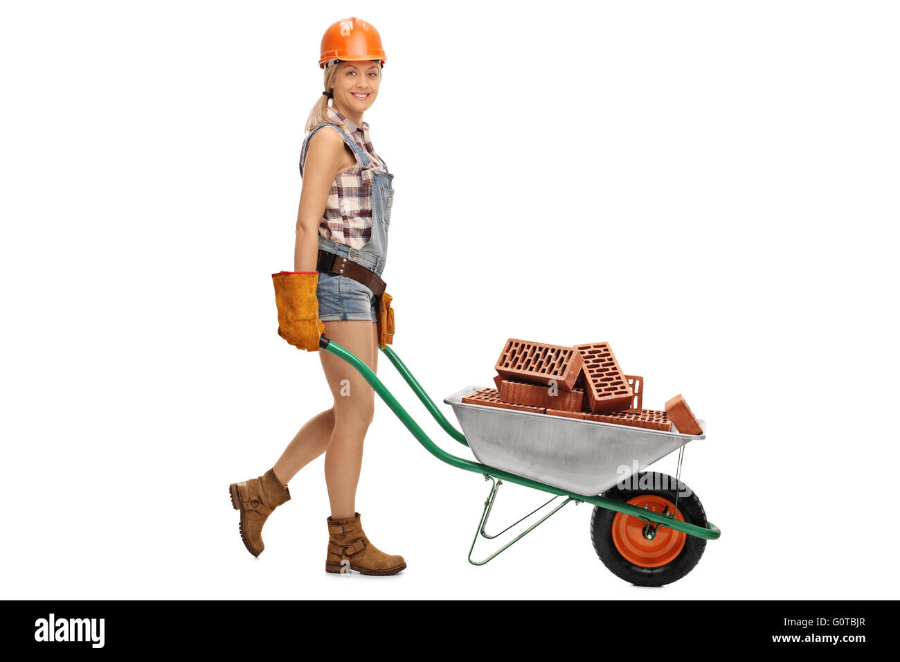 Female construction worker pushing a wheelbarrow full of bricks ...
