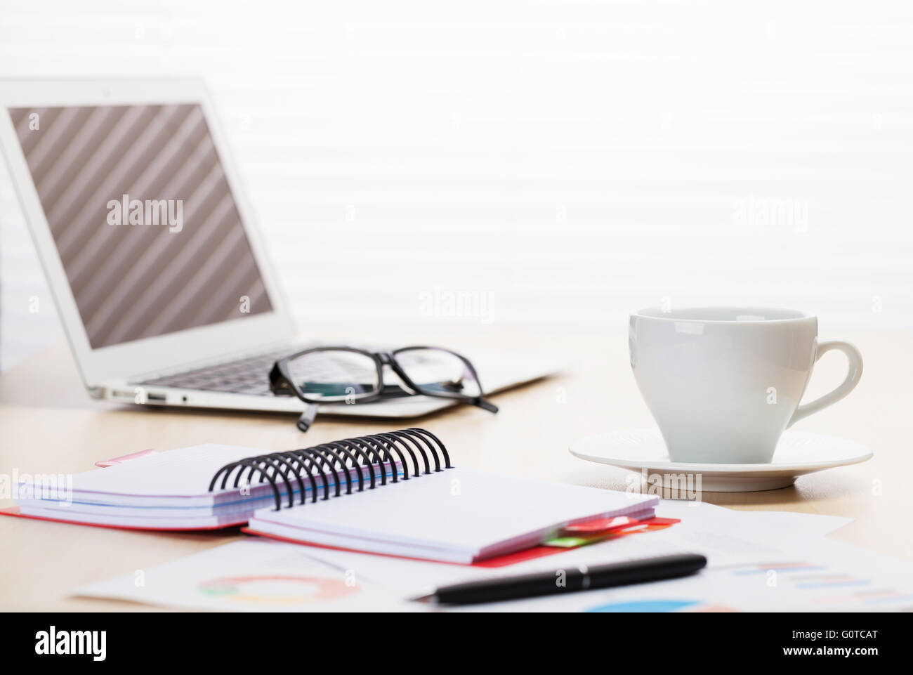 Office workplace with laptop, coffee cup, reports and notepad on desk ...