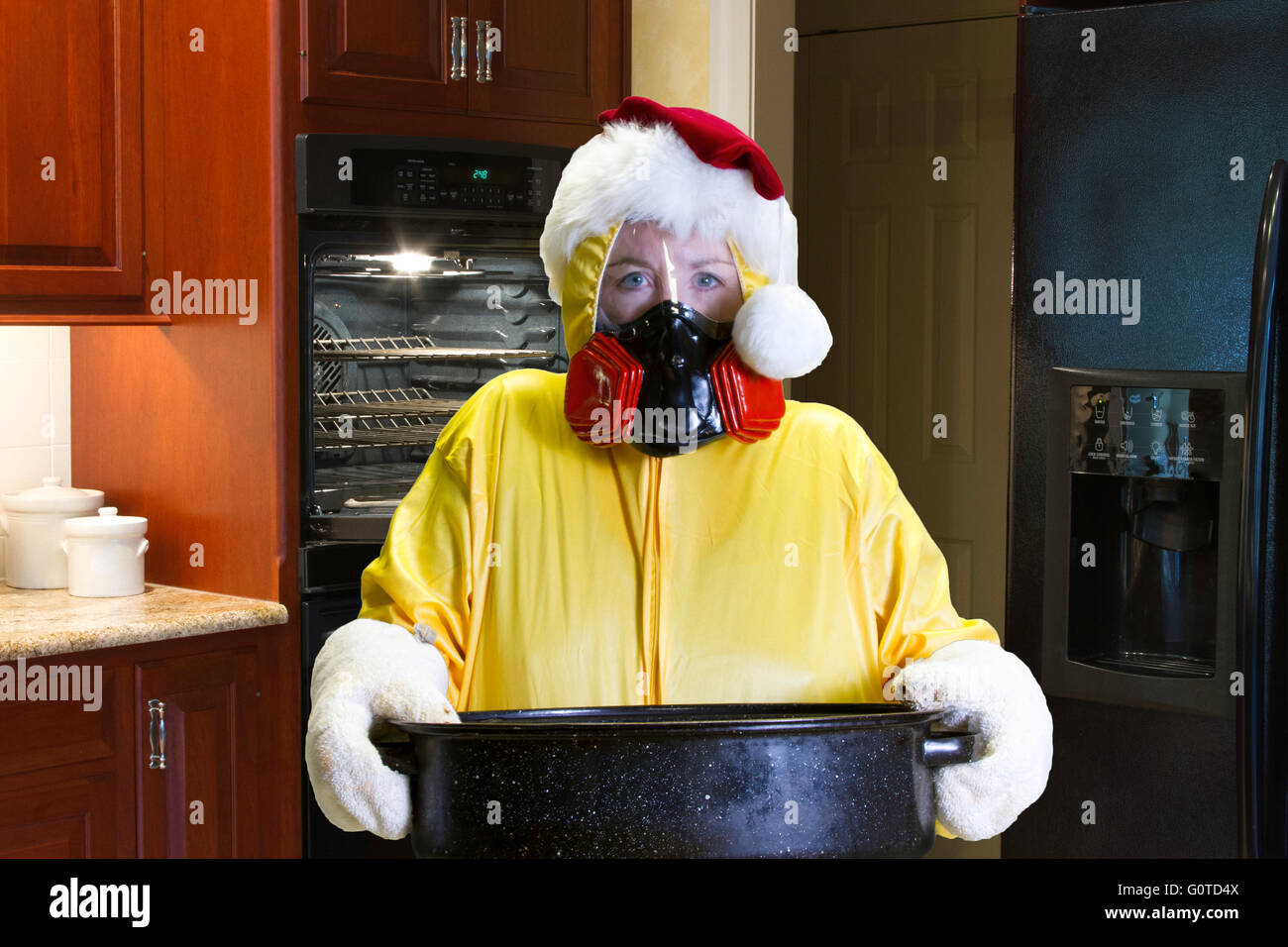Woman in yellow HazMat suit with respirator wearing a Santa hat holding ...