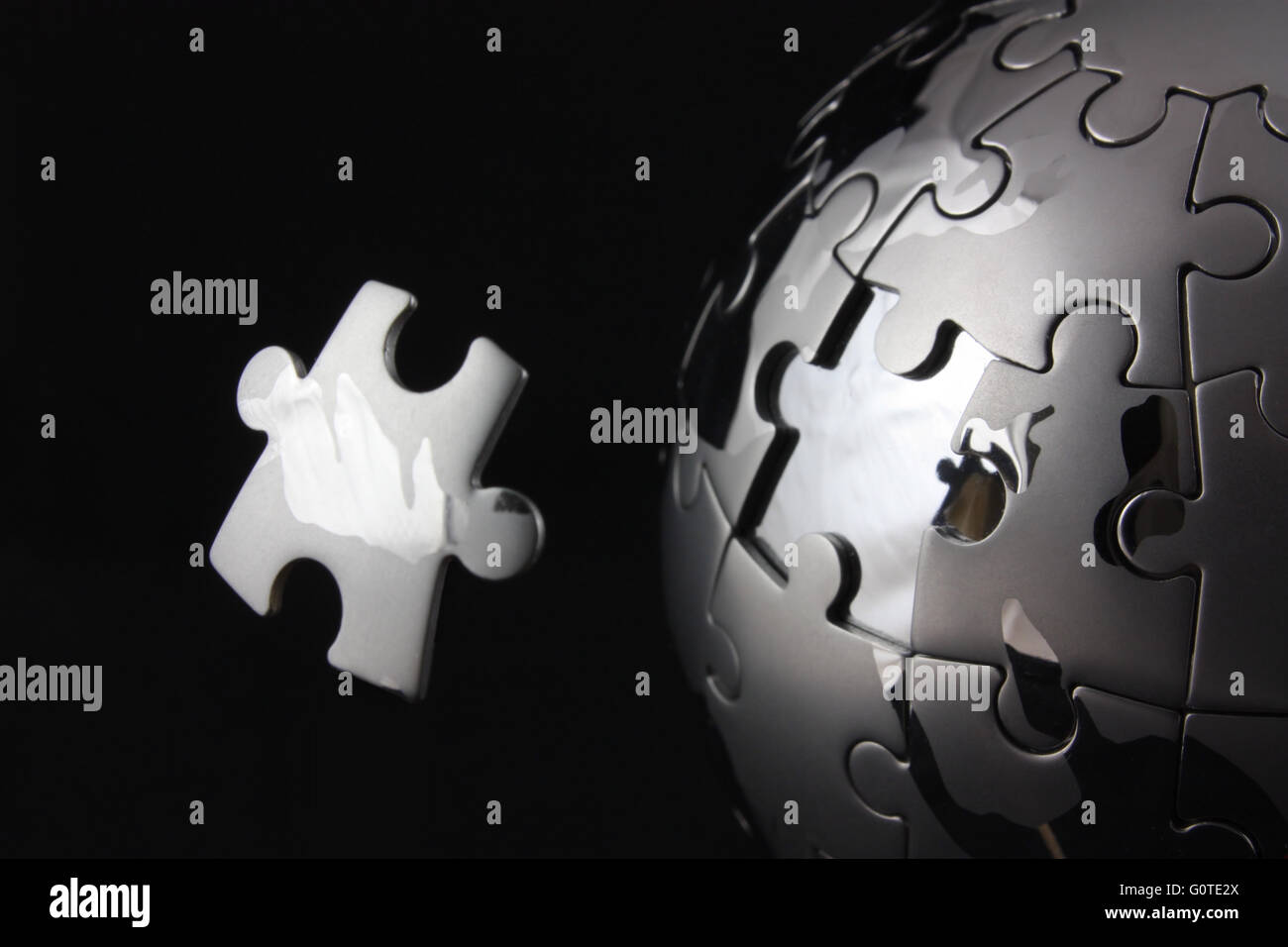 Floating jigsaw piece over chrome puzzle globe Stock Photo - Alamy