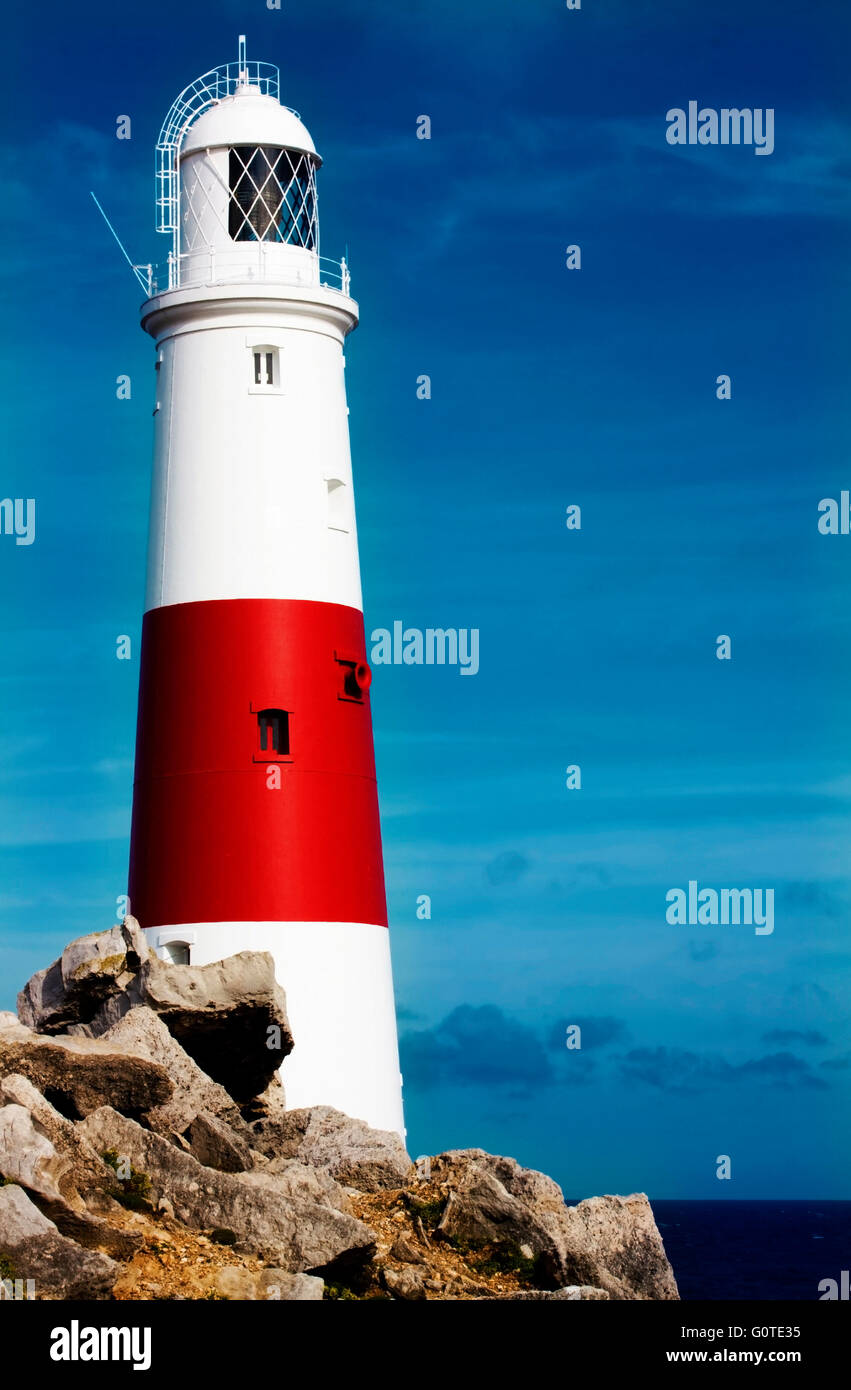 Lighthouse on rocks with light beams in the Isle of Portland in the UK ...