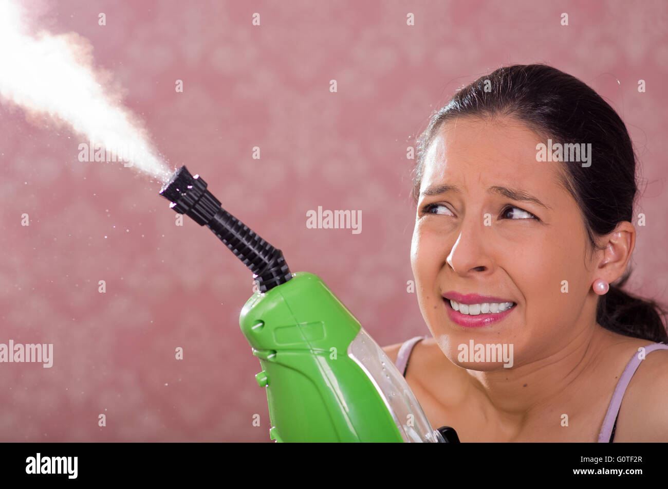 Brunette woman holding steam cleaner machine and vapor coming out ...