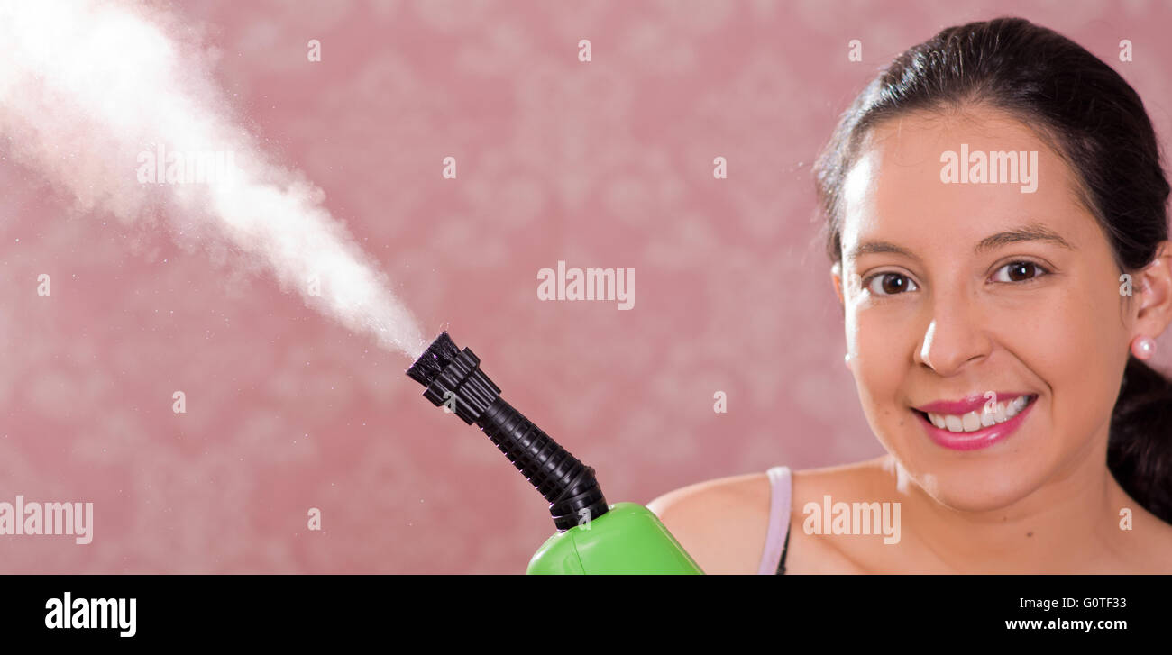 Brunette woman holding steam cleaner machine and vapor coming out ...