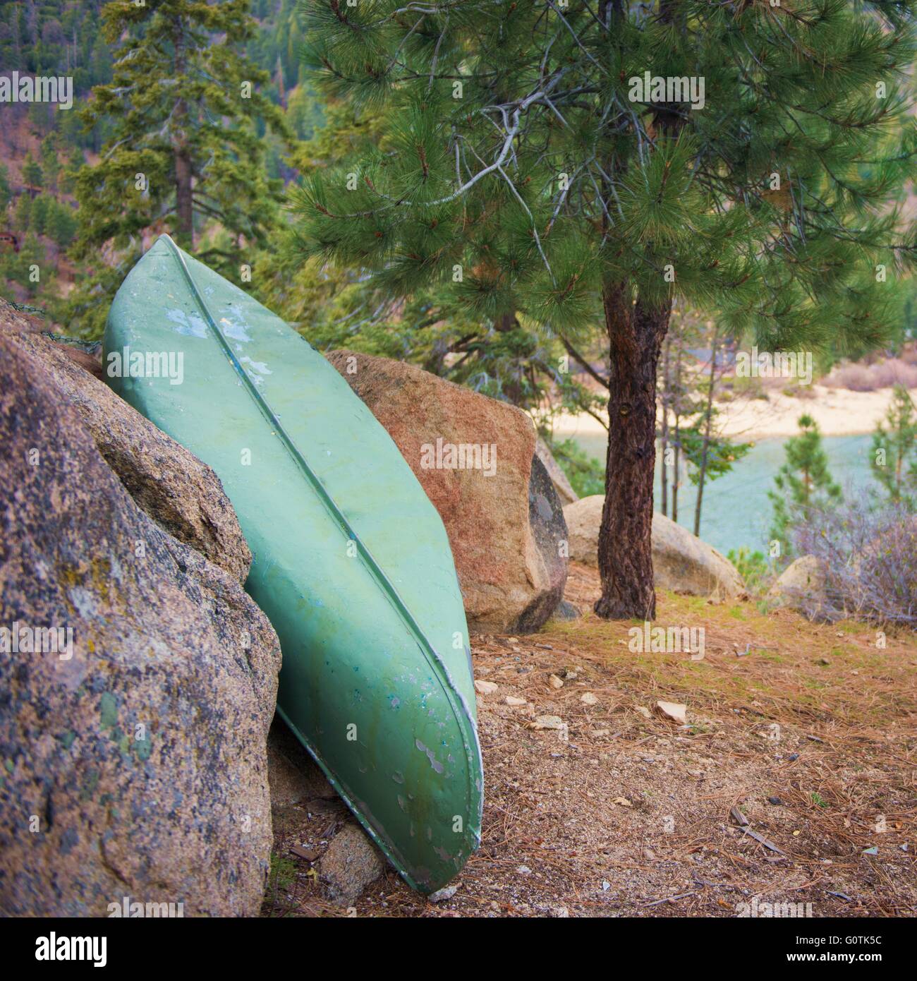 Canoe leaning against rocks by a lake Stock Photo - Alamy