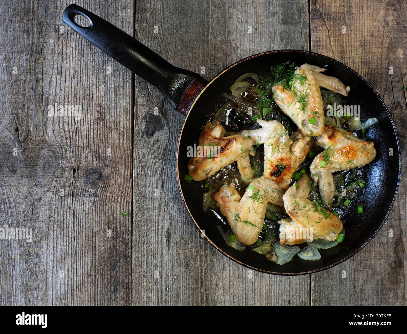 Fried chicken wings in frying pan on wooden table Stock Photo - Alamy