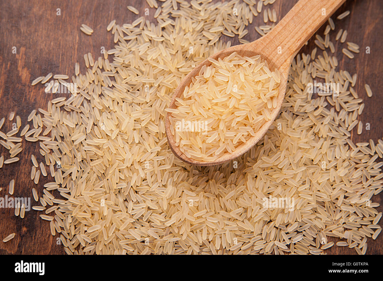 uncooked rice with spoon and woody background Stock Photo - Alamy