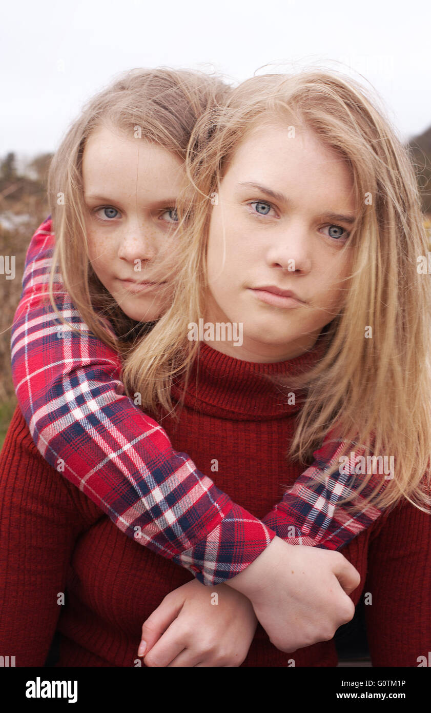 Two sisters embracing both looking straight to camera Stock Photo - Alamy