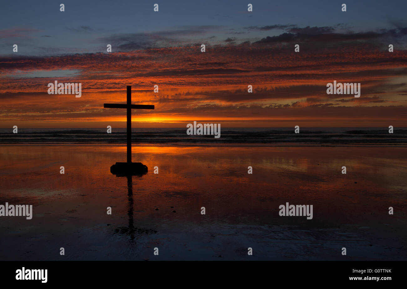 Cross on a beach with the sun setting down behind it Stock Photo - Alamy