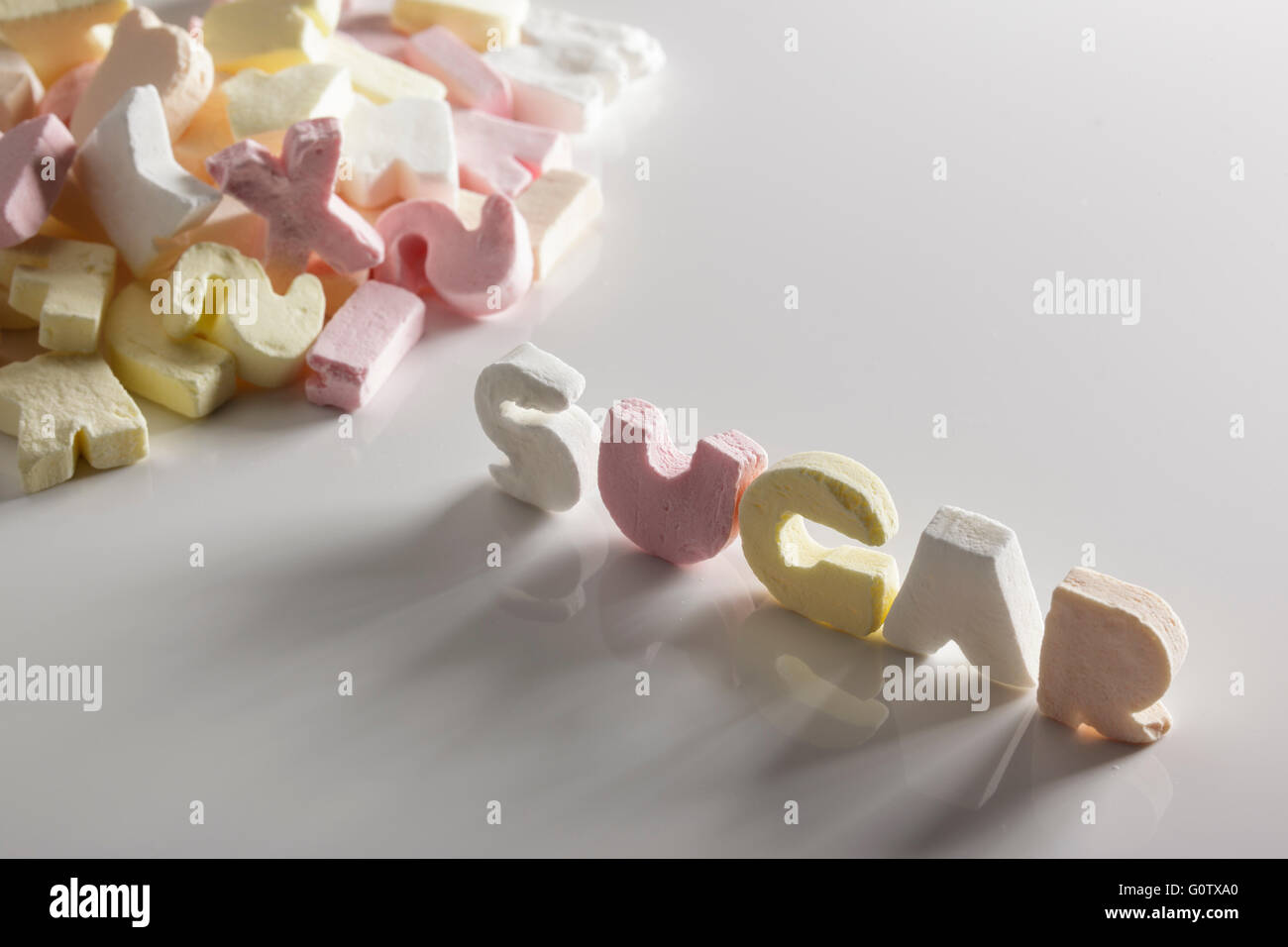 Pile of alphabet candy with letters forming the word sugar against a ...