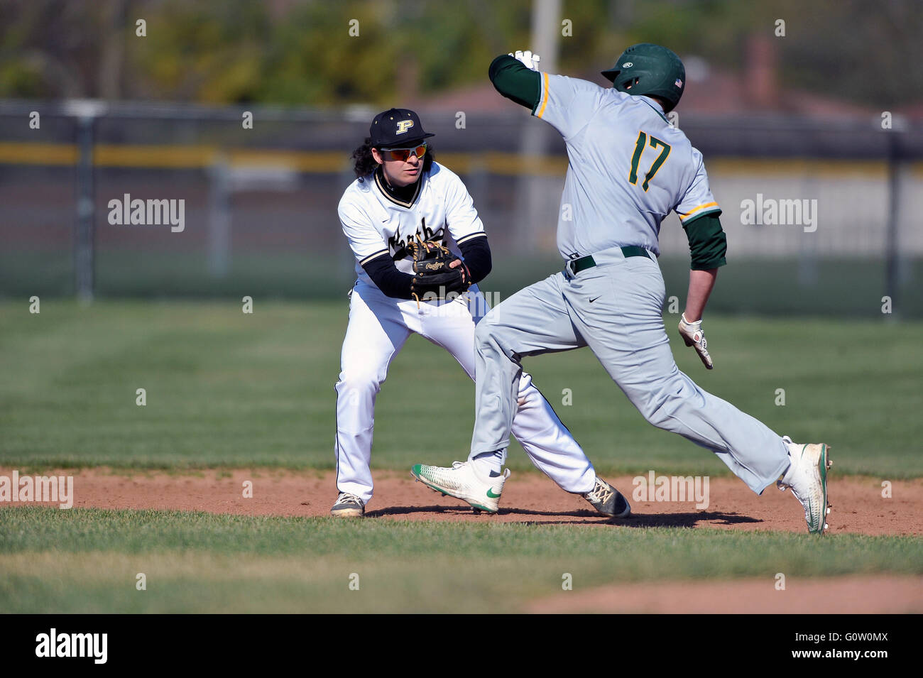 After fielding a ground ball, a second baseman moving to apply a tag to ...