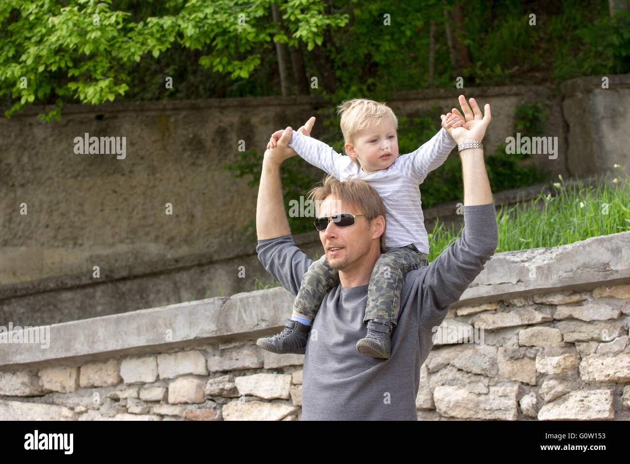 Blond boy sitting on fathers shoulder outdoors Stock Photo - Alamy
