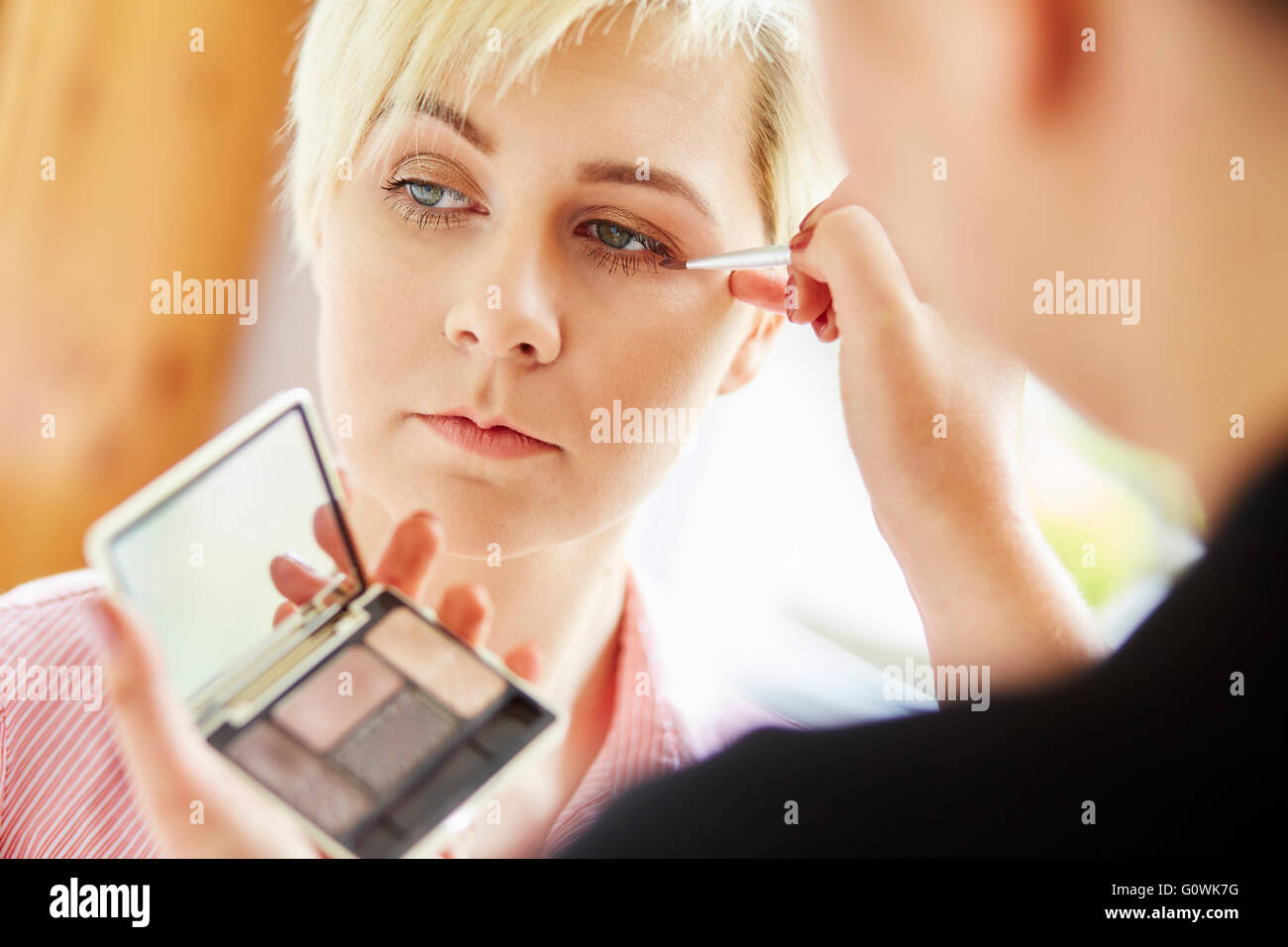 Woman applying make up to another Stock Photo - Alamy