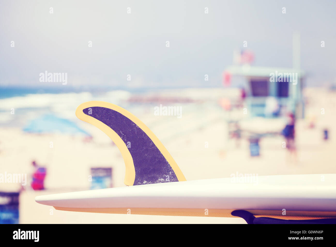 Vintage toned surfboard fin with lifeguard tower in distance, shallow ...