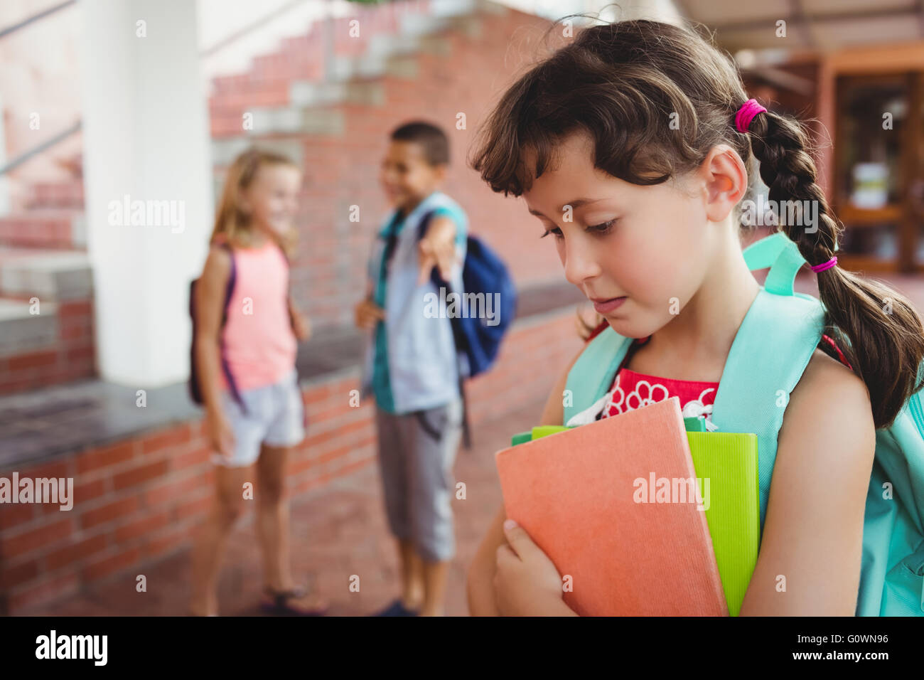 Brunette girl mocked by two children behind her Stock Photo - Alamy