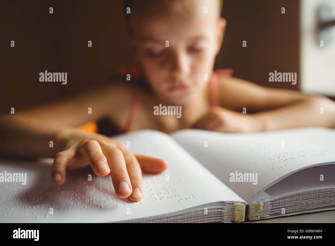 Little girl using his right hand to read braille Stock Photo - Alamy
