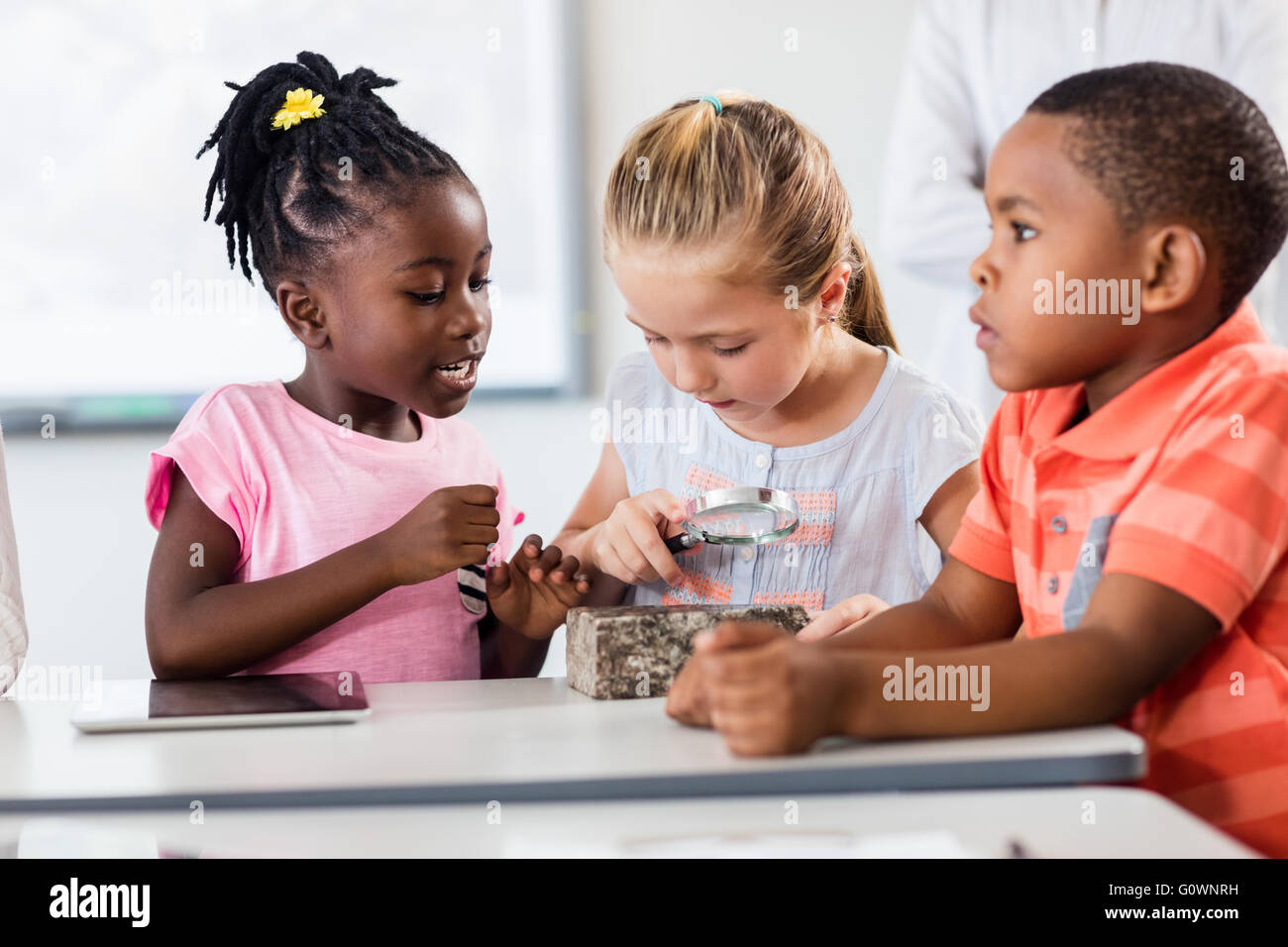 Pupils looking at rock with magnifying glass Stock Photo - Alamy