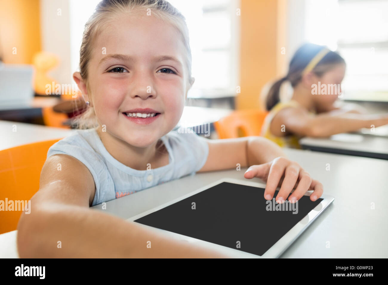 Cute girl posing at desk with tablet pc in classroom Stock Photo - Alamy