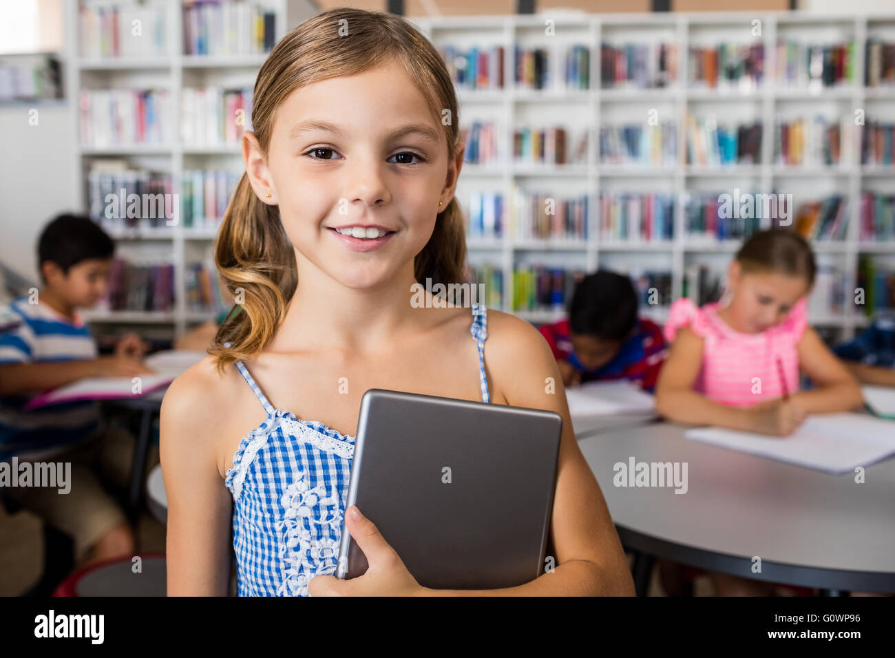 A cute little girl smiling at the camera with tablet pc Stock Photo - Alamy