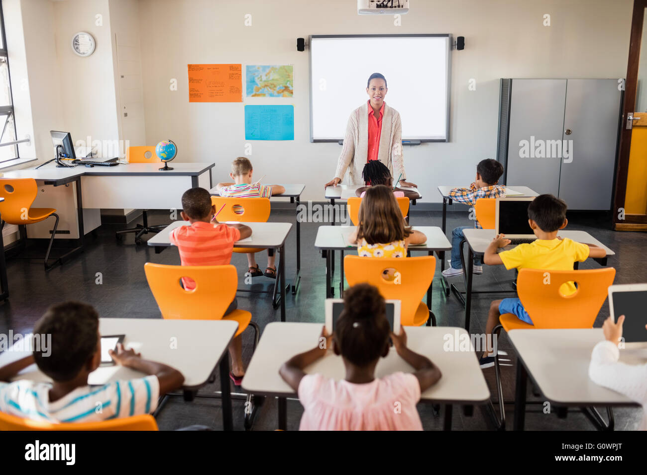 Teacher giving lesson to her students Stock Photo - Alamy