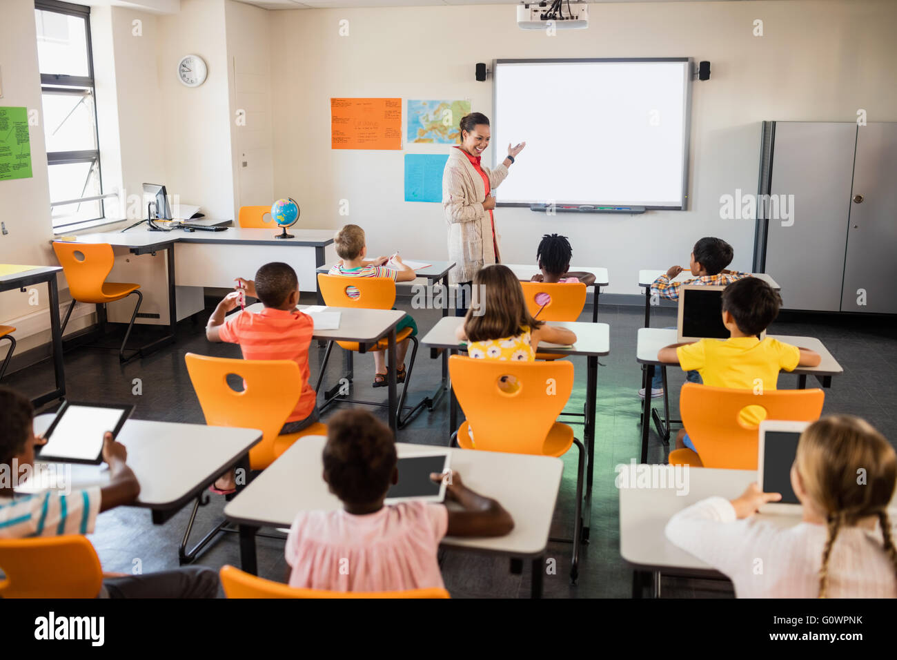 Teacher giving lesson to her students Stock Photo - Alamy