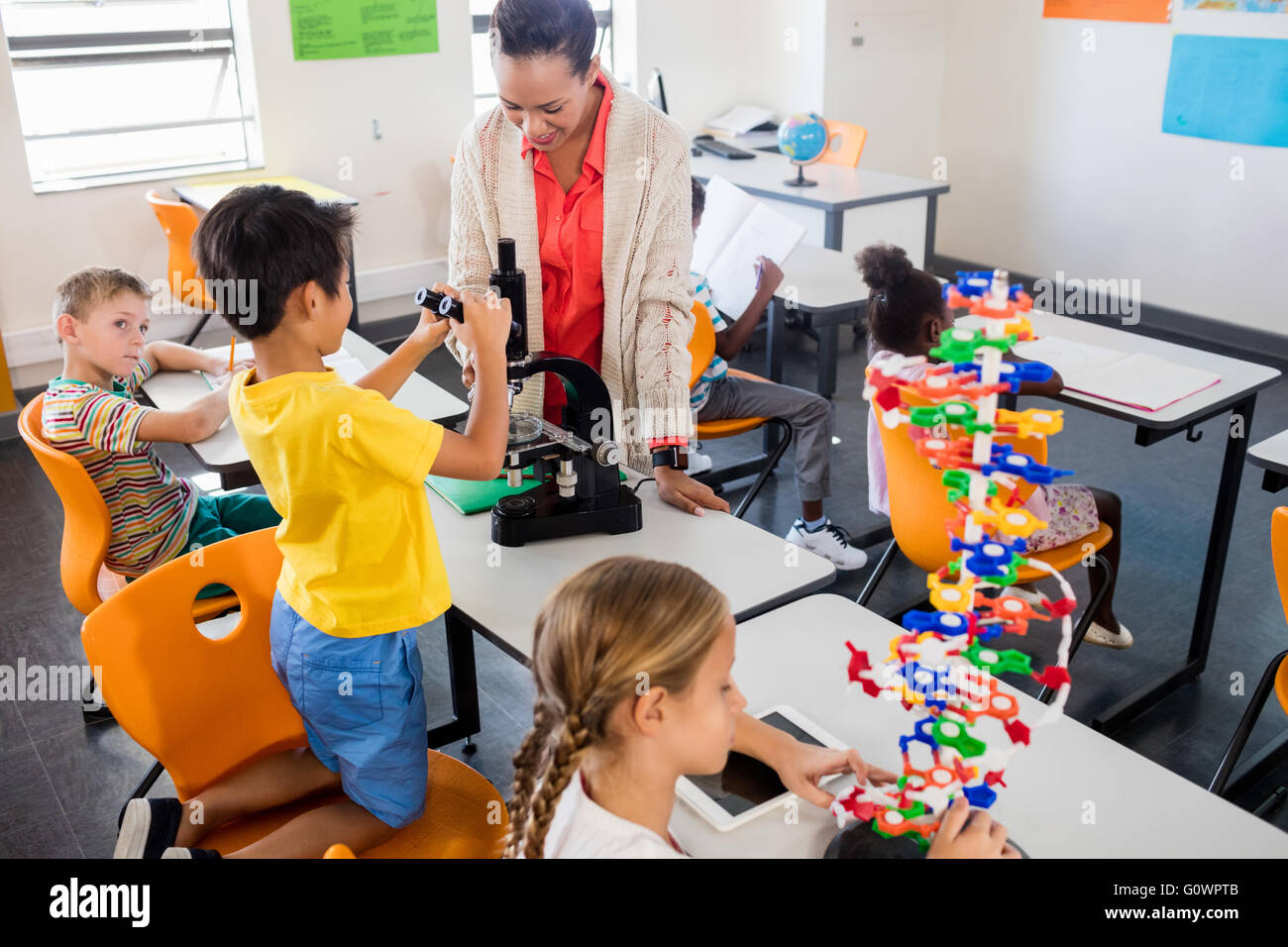 Teacher giving lesson to her students Stock Photo - Alamy