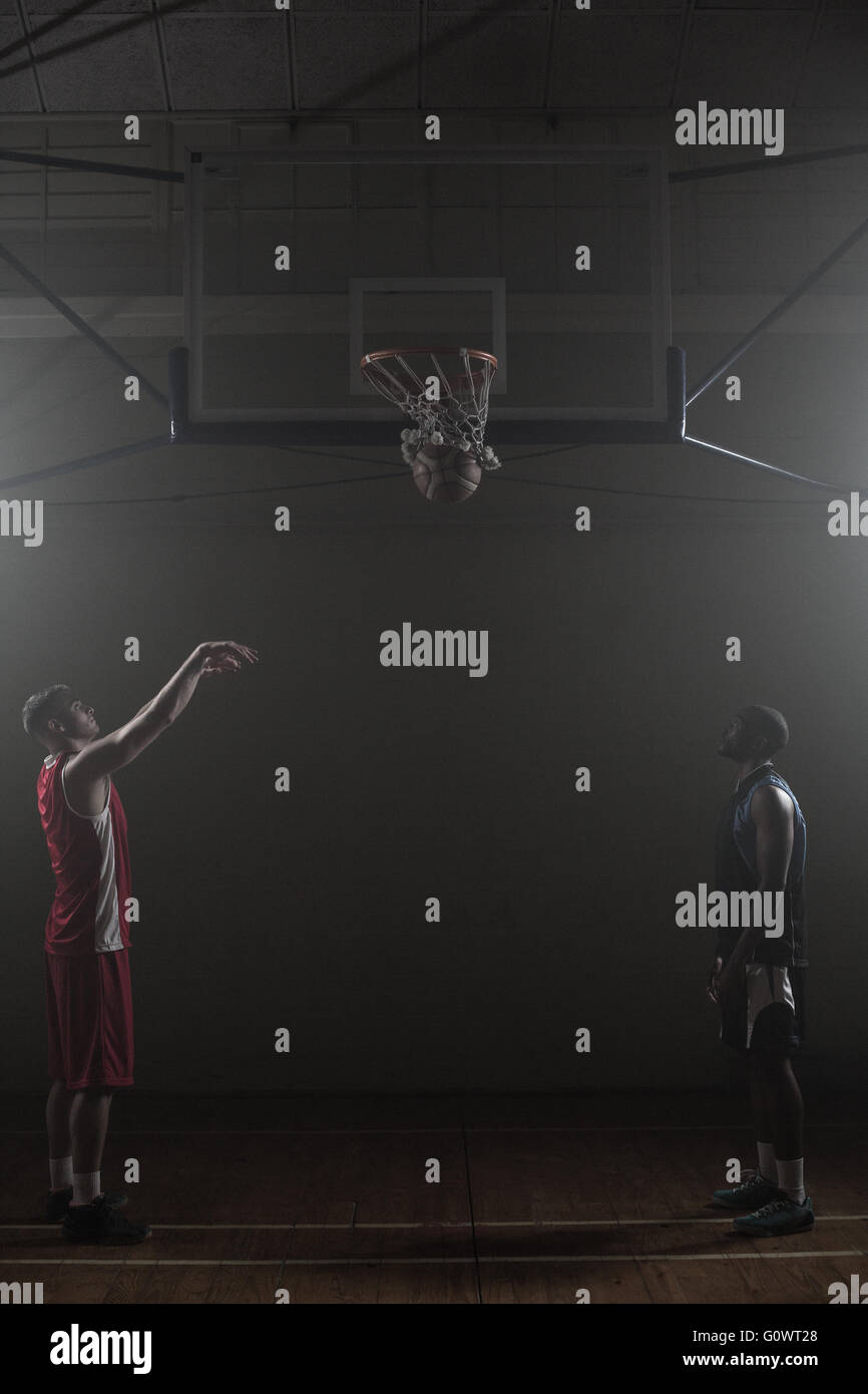Two basketball player in a gymnasium with one scoring a shoot Stock ...