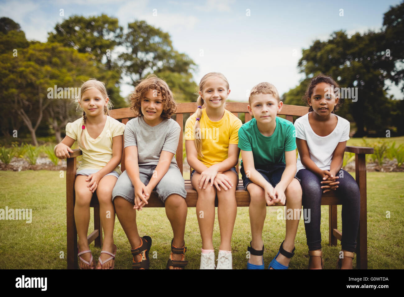 Happy children sitting on a bench Stock Photo - Alamy