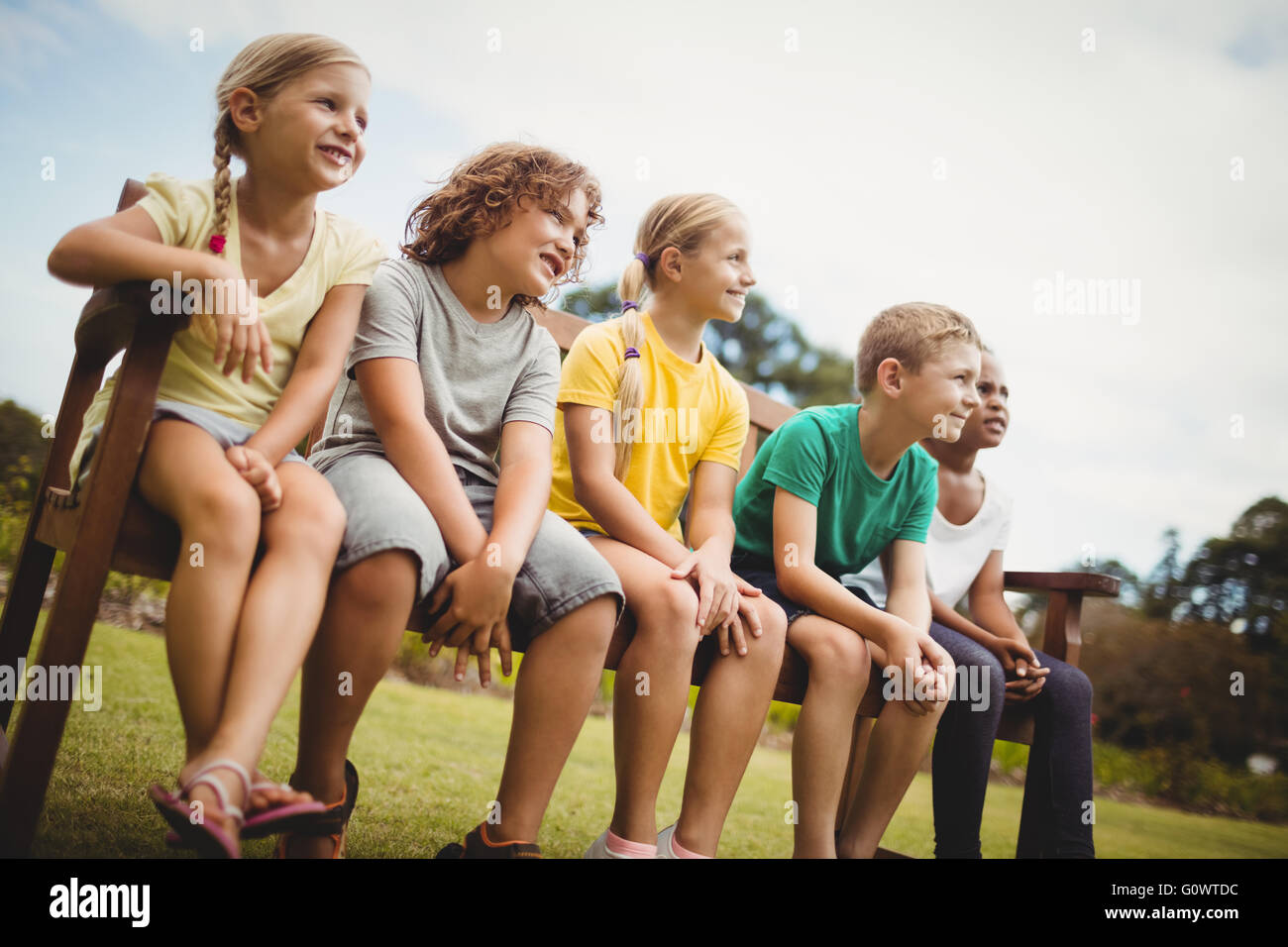 Happy children sitting on a bench Stock Photo - Alamy