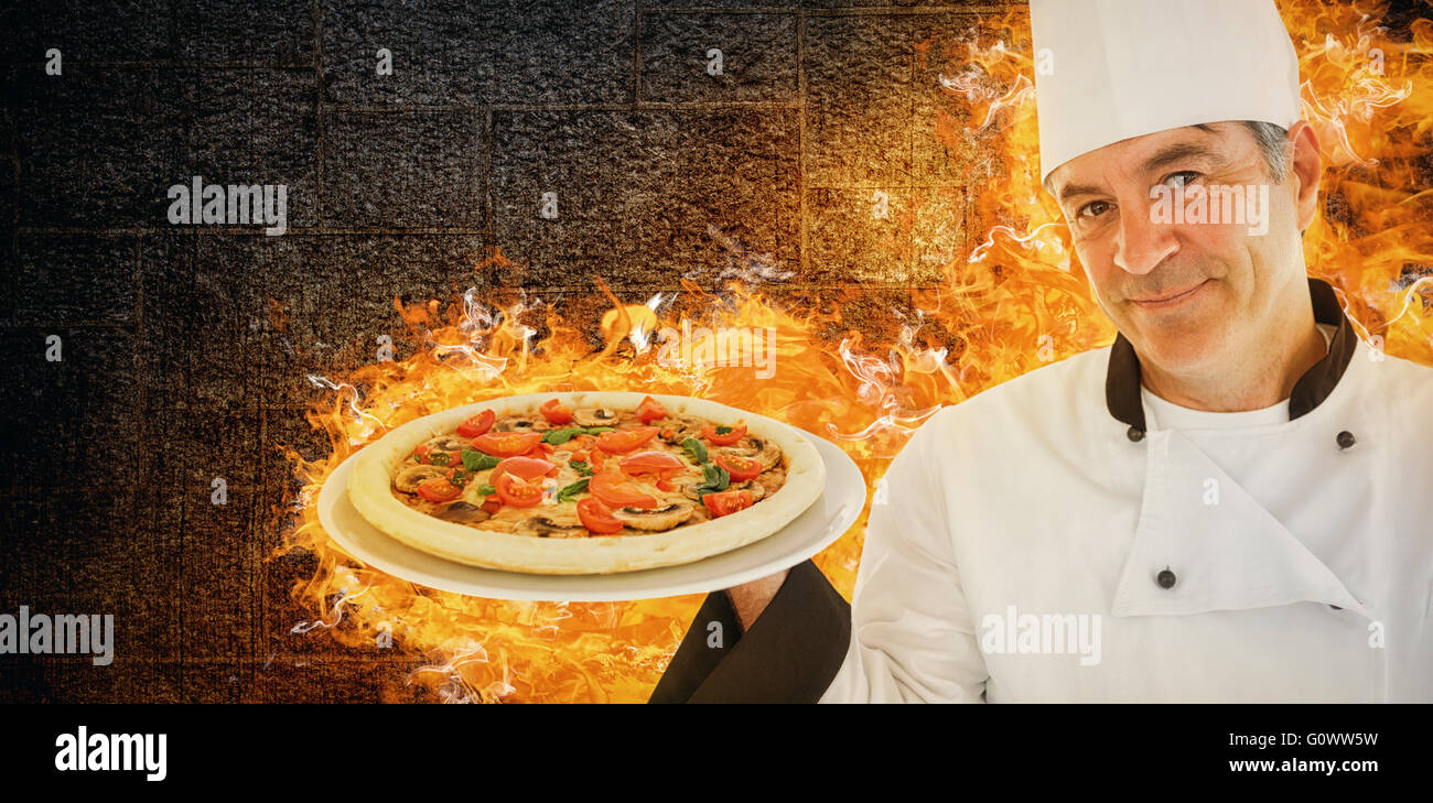 Composite image of friendly chef holding a pizza Stock Photo - Alamy