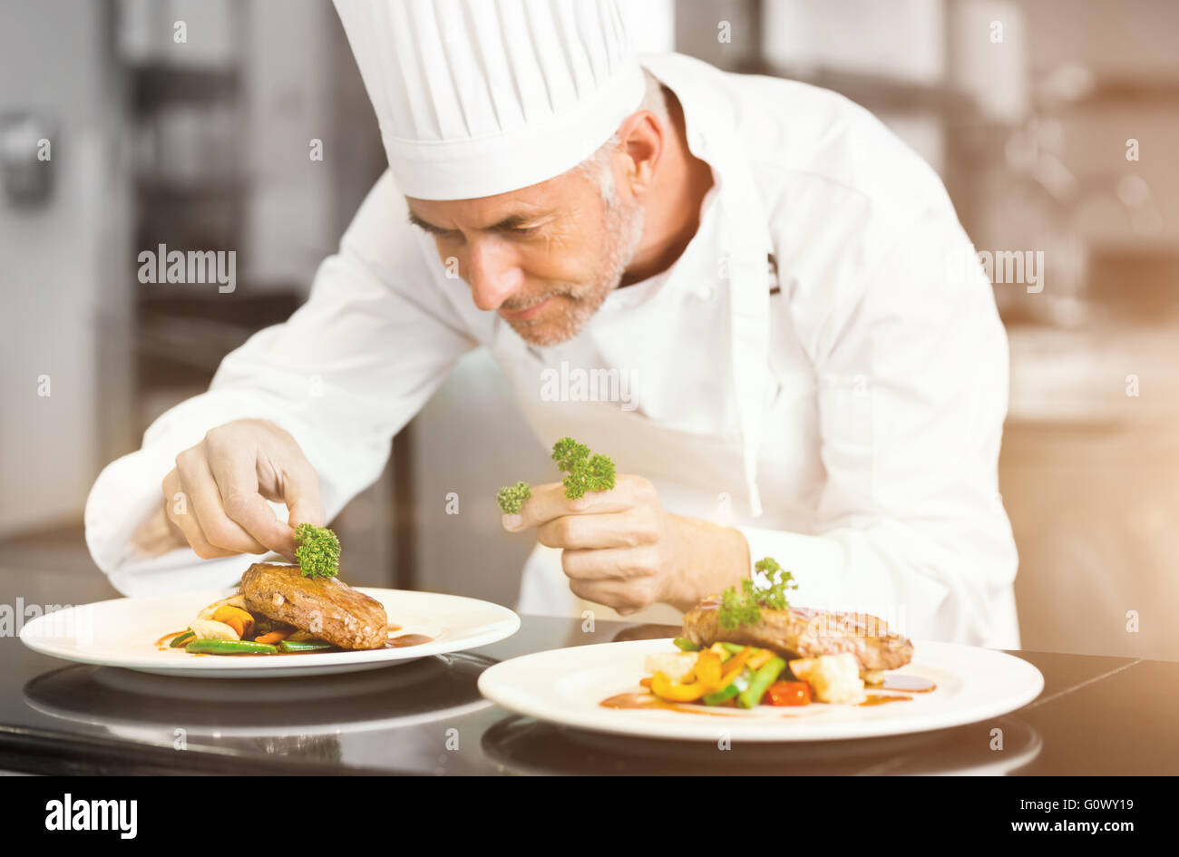 Concentrated male chef garnishing food in kitchen Stock Photo - Alamy