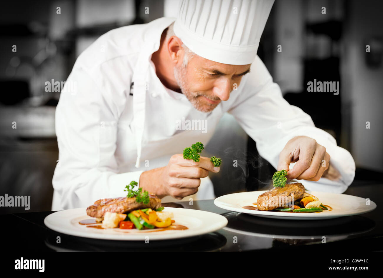 Concentrated male chef garnishing food in kitchen Stock Photo - Alamy