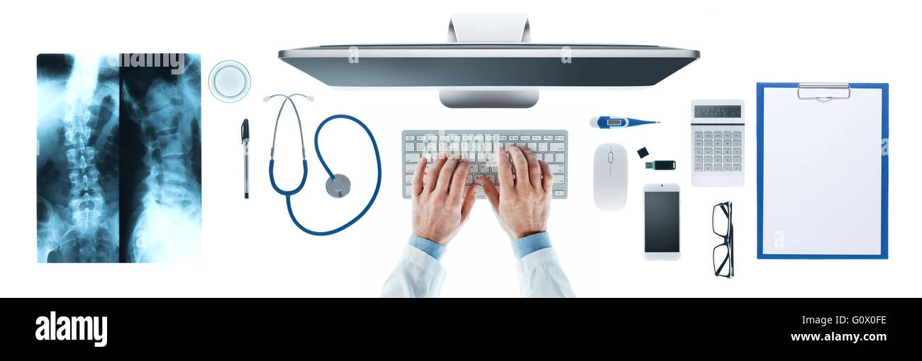 Doctor at desk working at computer with medical equipment on white ...