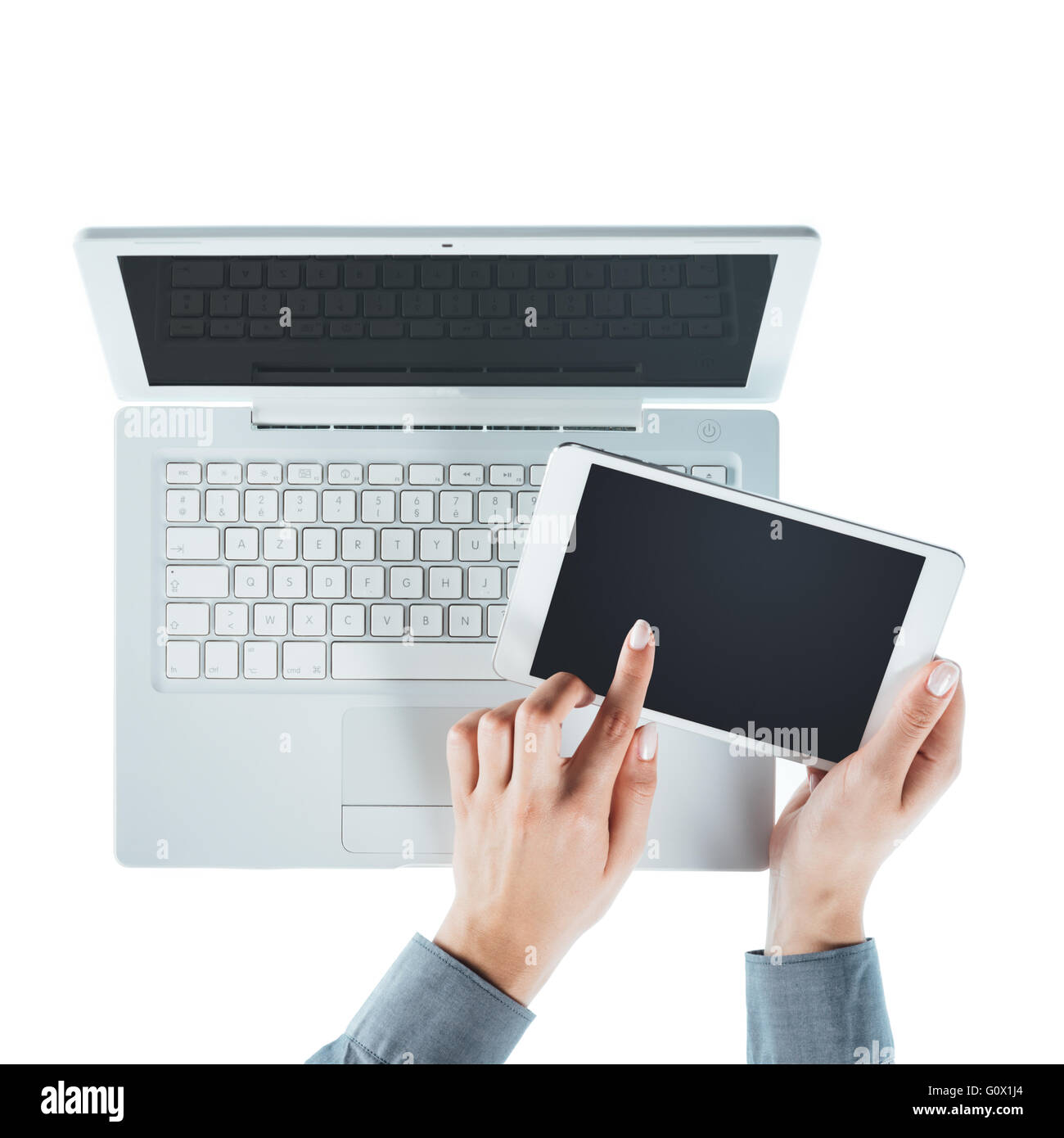 Female hands using a touch screen tablet and a laptop on white ...