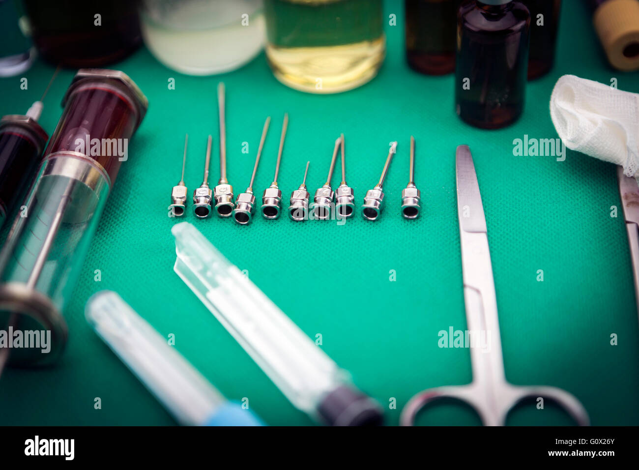 Needles metal of various sizes next to syringes in a table of operating ...