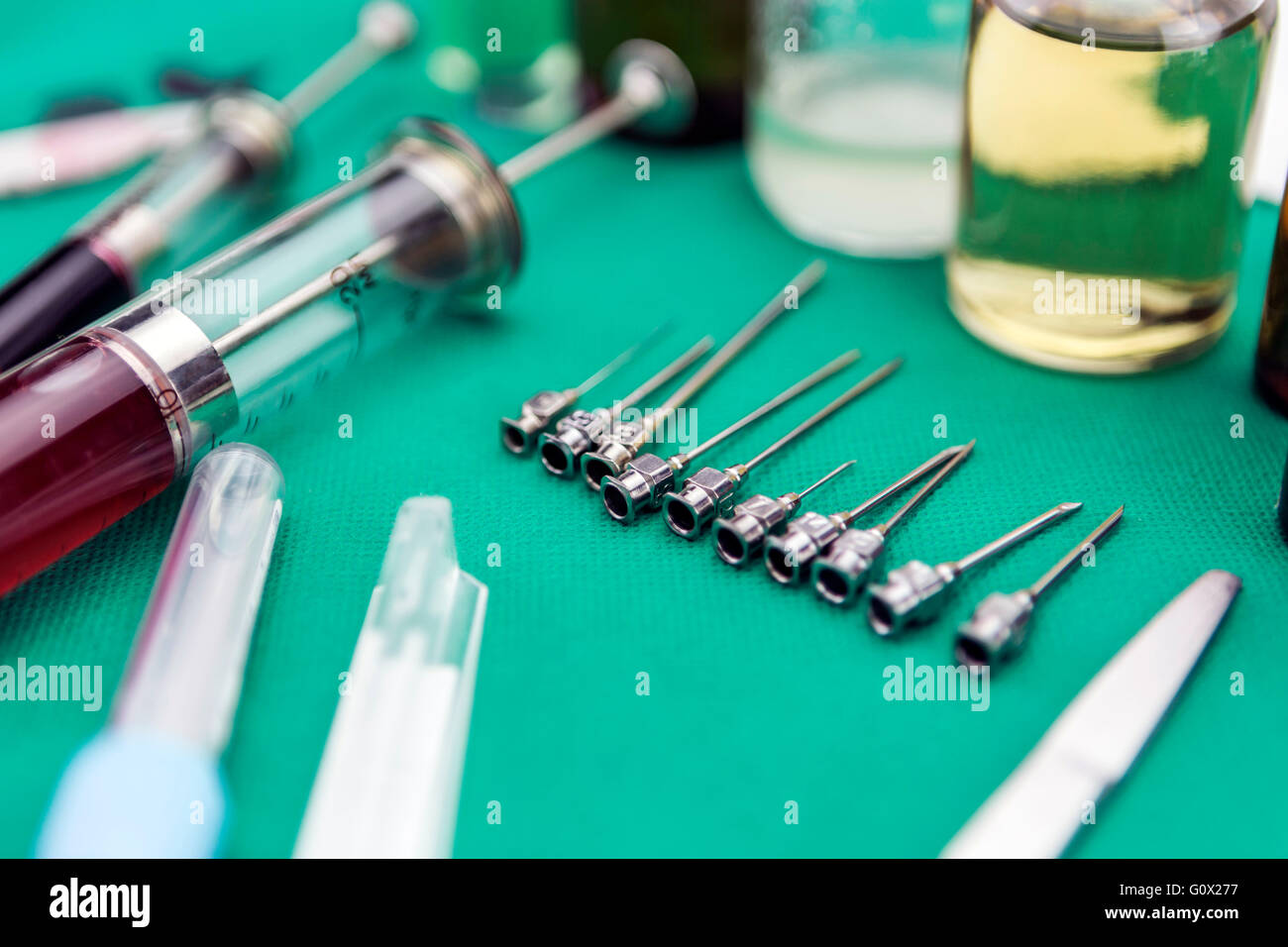 Needles metal of various sizes next to syringes in a table of operating ...