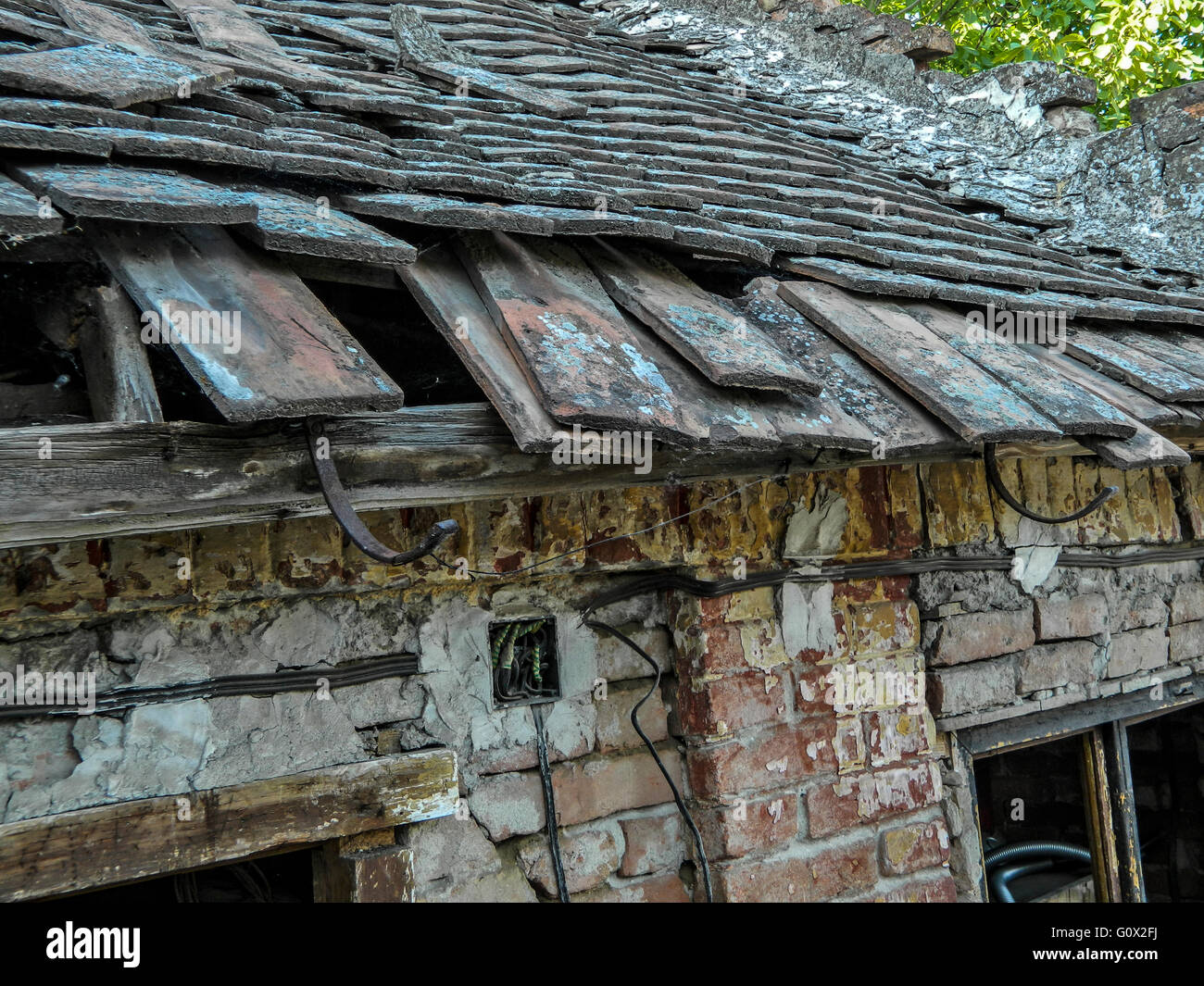 A decrepit old house with a damaged and devastated roof and tiles Stock ...