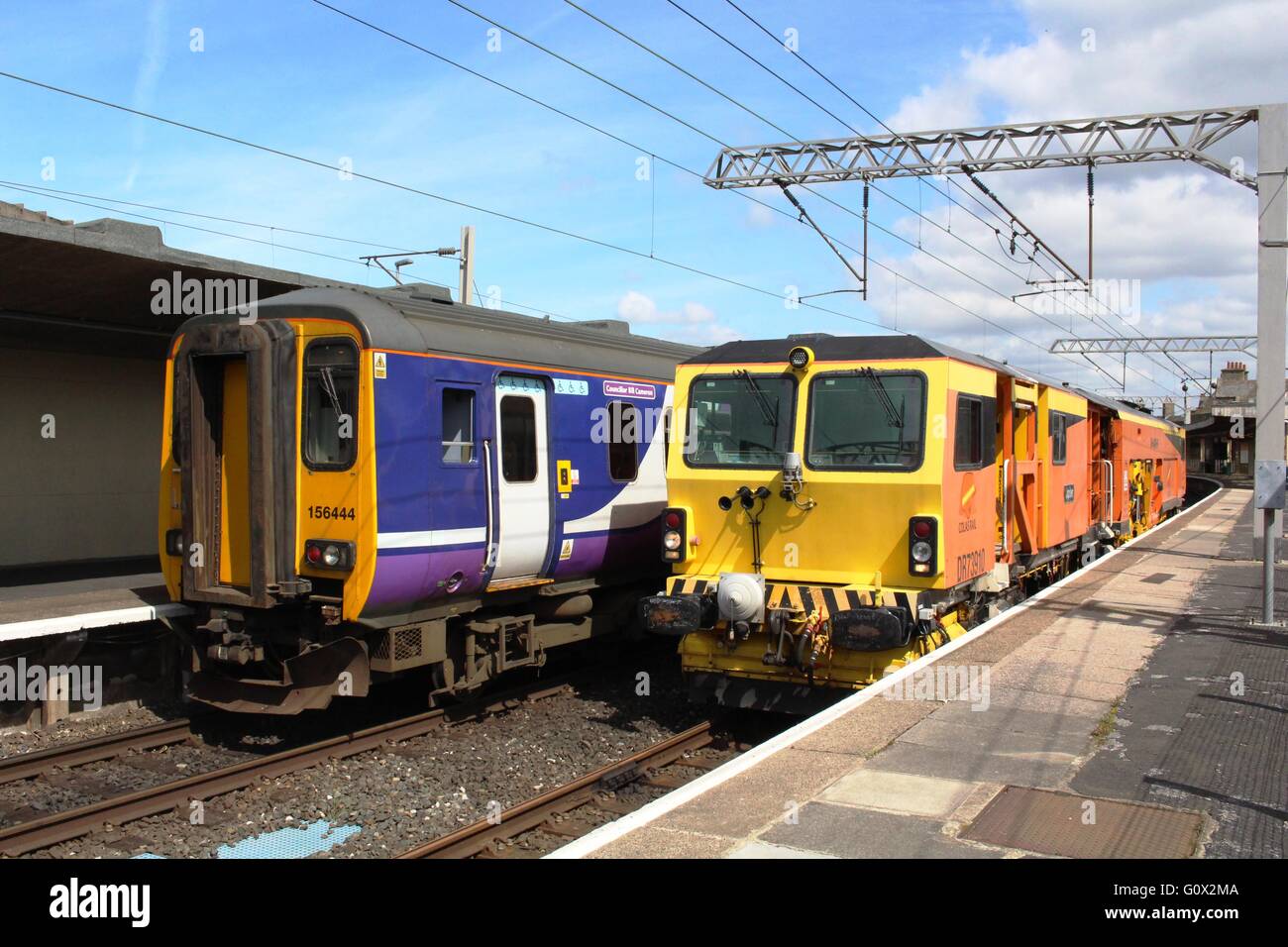 Class 156 diesel multiple unit passes a track machine as it enters ...