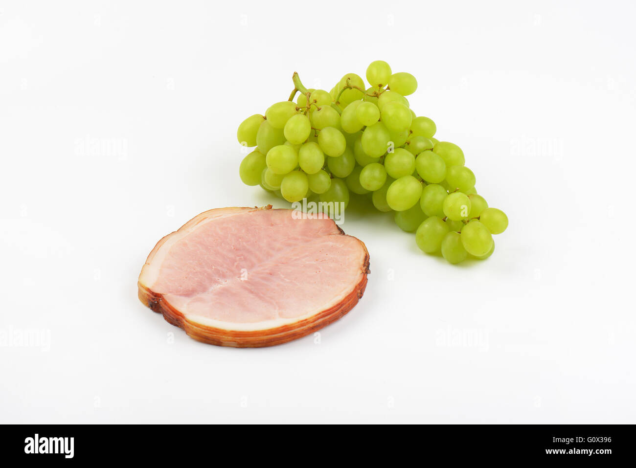 stack of ham slices and bunch of white grapes on white background Stock ...