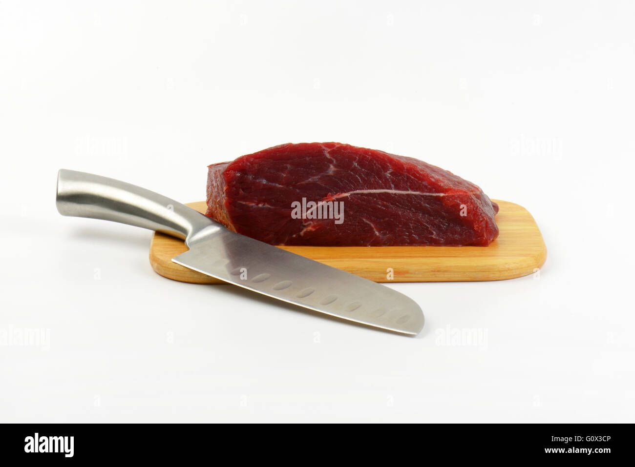 chunk of raw beef meat and sharp knife on wooden cutting board Stock ...
