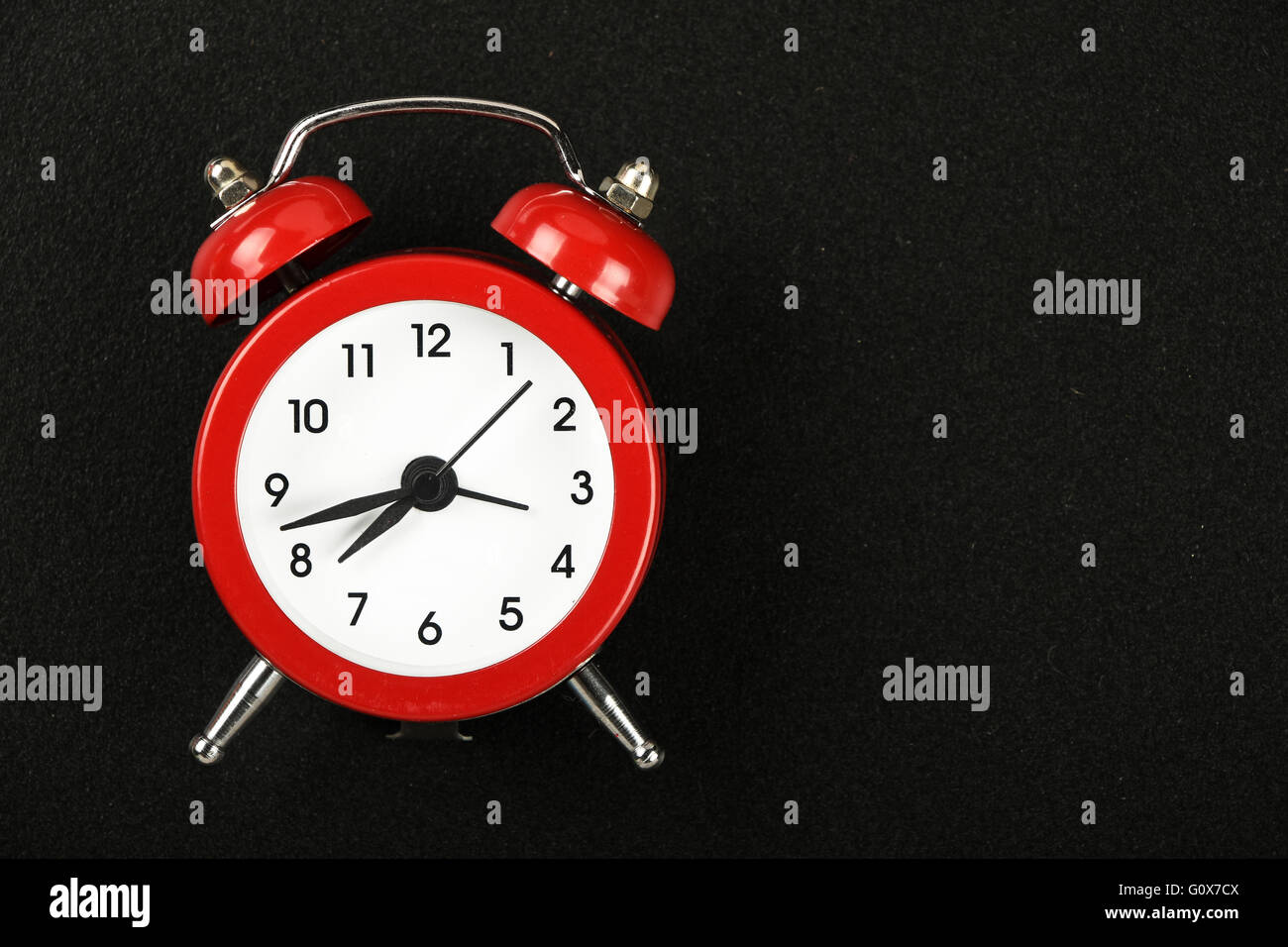 Time concept, small red metal alarm clock with red bells over black ...